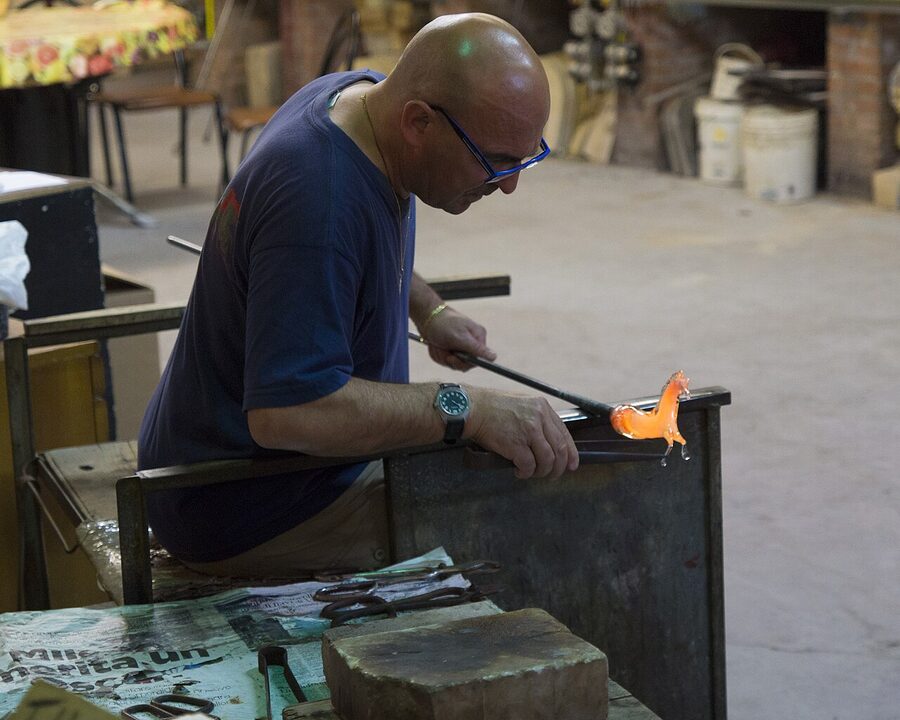 Murano glassblower shaping molten glass with traditional tools
