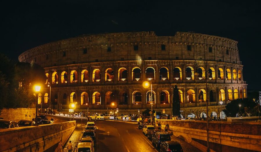 Colosseum at night with cars on the road in front