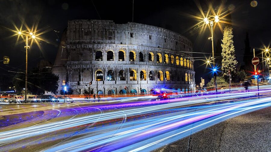 Colosseum at night with car light trails on the road