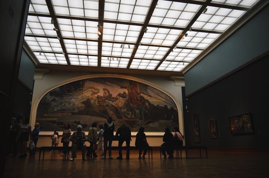Visitors gathered in front of large-scale artwork in a dim museum gallery