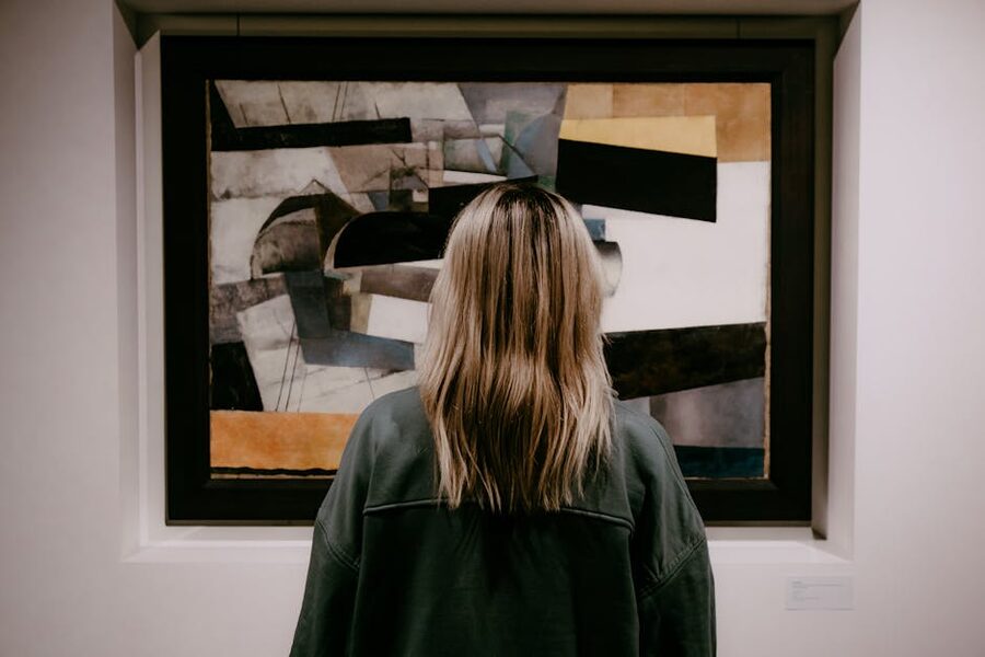 Visitor viewing an abstract painting from behind in an art gallery