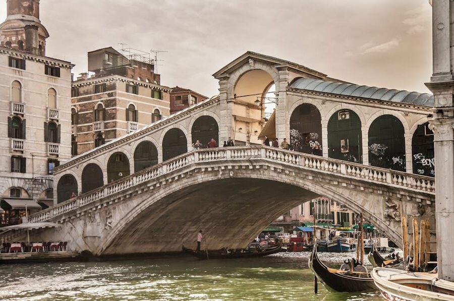 People walking on the Rialto Bridge with gondolas below
