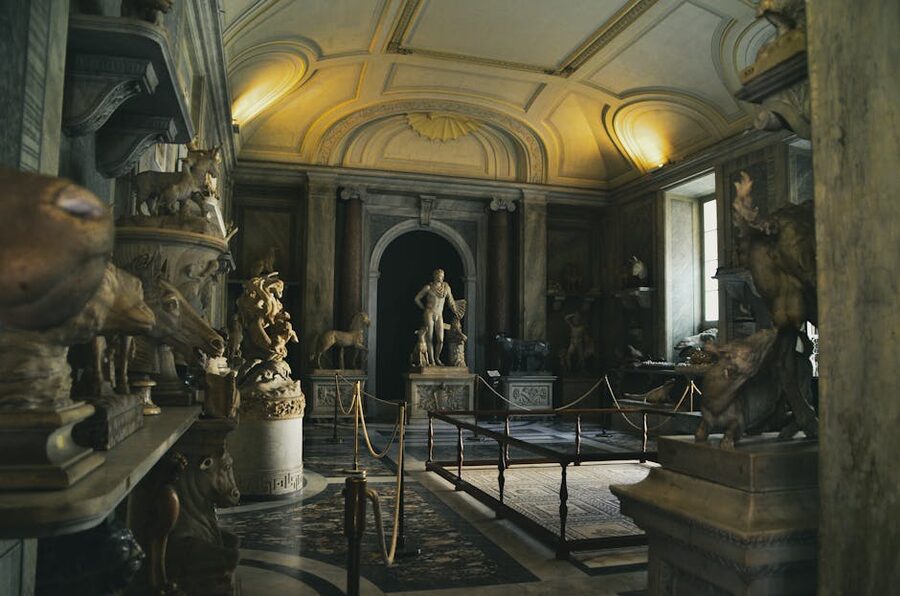 Visitors walking through a classical Roman sculpture gallery interior
