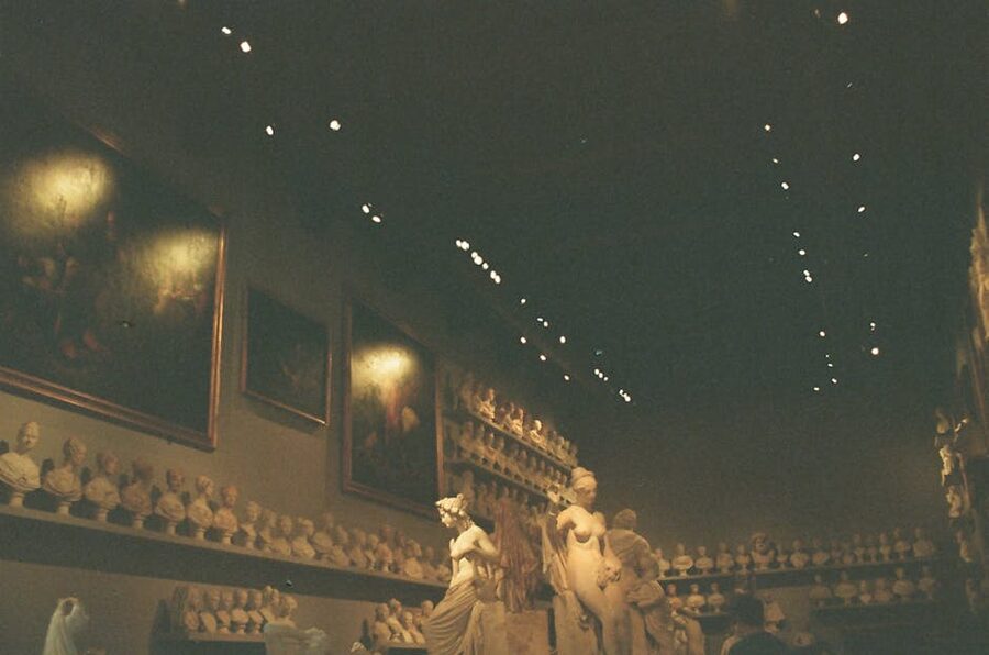 Dimly lit museum gallery interior with sculptures and paintings