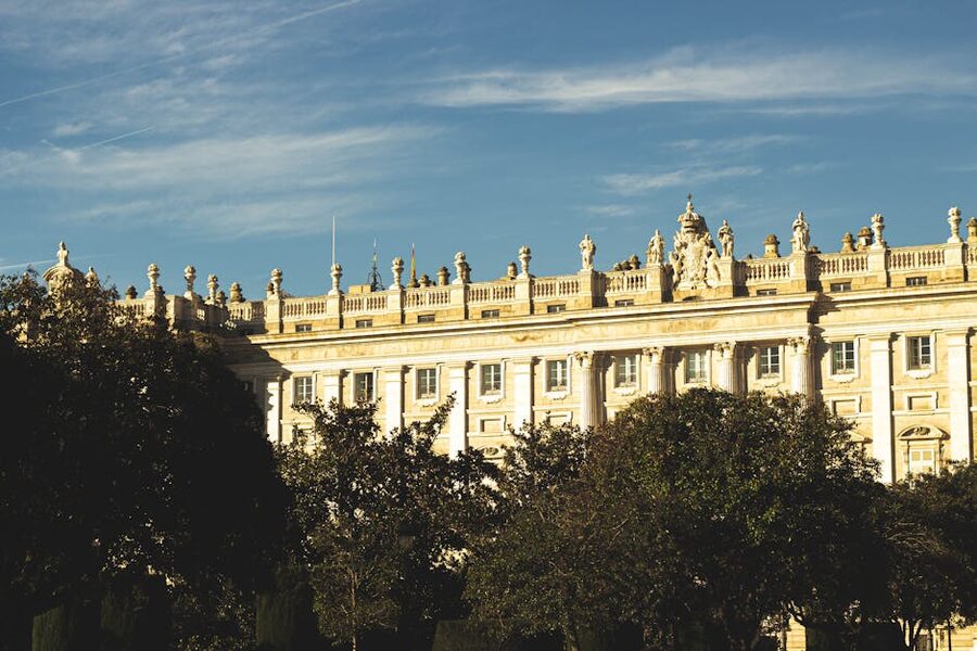 Sunlit view of the Royal Palace of Madrid with classic architecture and greenery