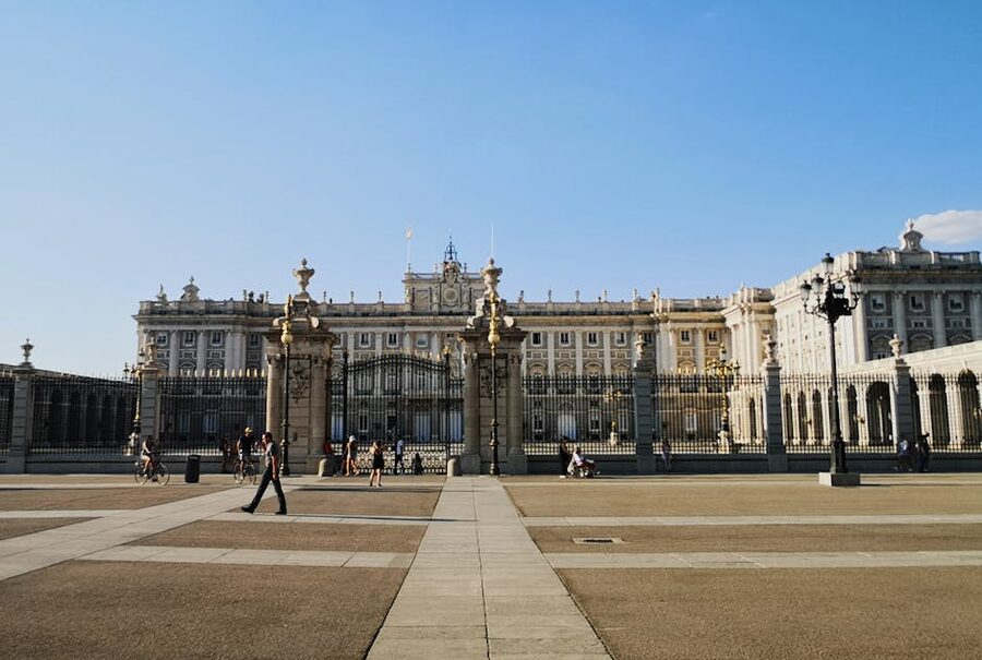 Royal Palace Madrid with people strolling under blue sky