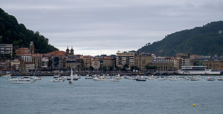 Boats in the small fishing harbour of San Sebastián with historic buildings behind