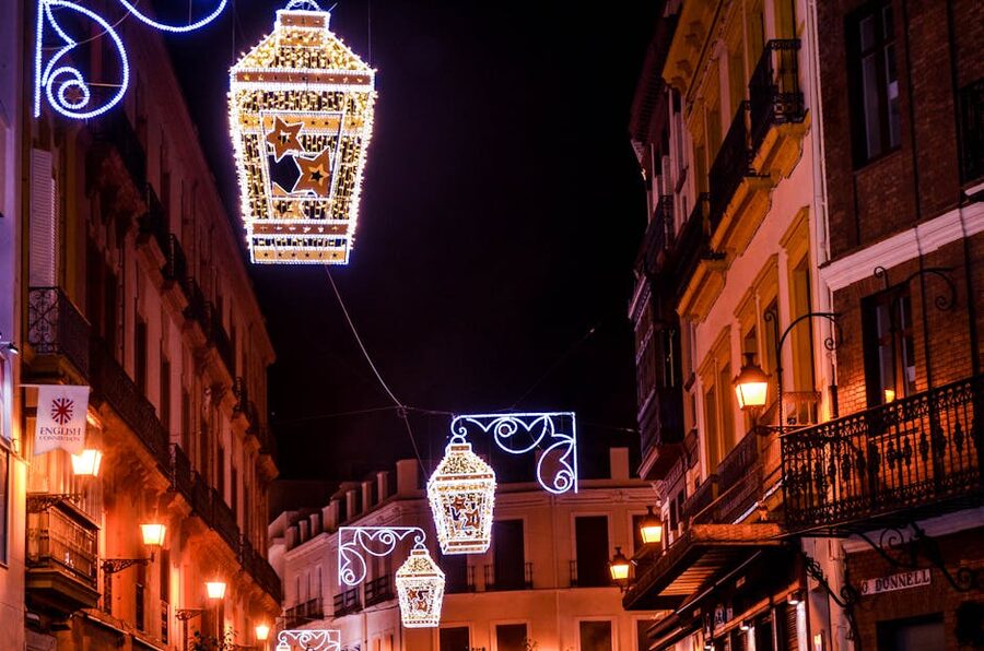 Seville old town lanterns hanging over a narrow historic street in the evening