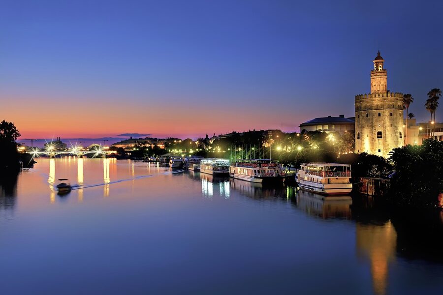 Seville Guadalquivir river at night with city lights reflecting