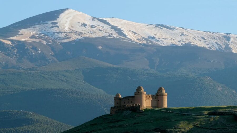 La Calahorra Castle on hill against snow capped Sierra Nevada Spain