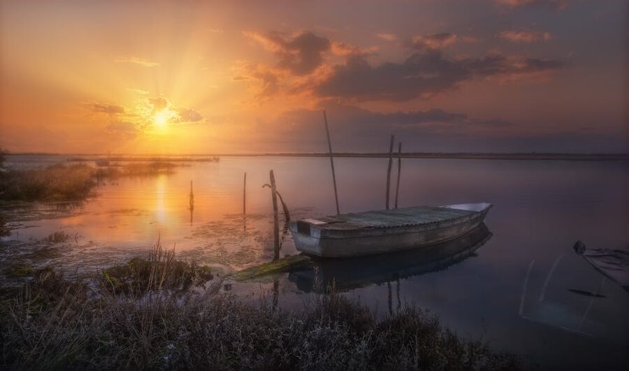 Venetian lagoon at sunset with a small boat reflecting on the water