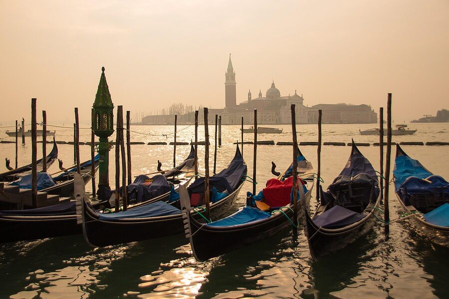 Venice gondolas reflected on still water at sunrise
