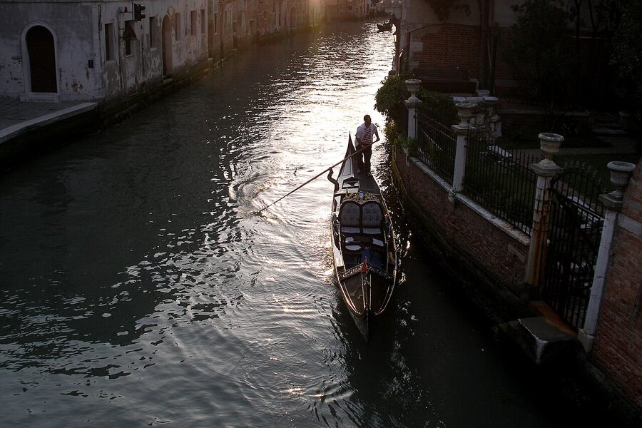 A gondolier rowing his boat in evening sunlight in Venice