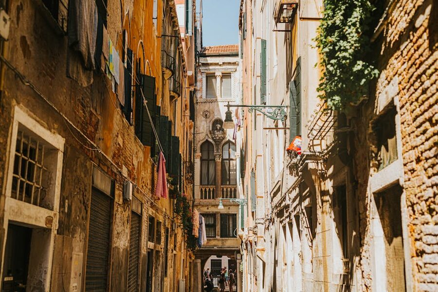 Laundry hanging across a narrow Venice alley with a couple walking