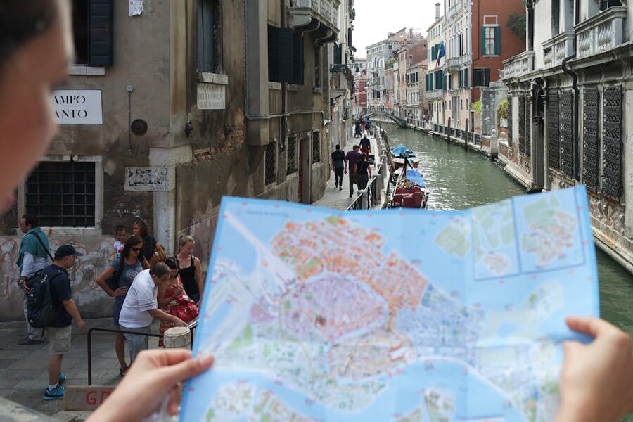 Tourists exploring Venice with a paper map in hand near a canal