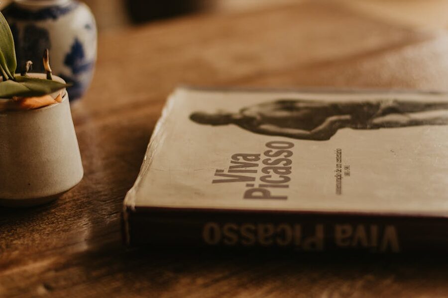 Viva Picasso book on a wooden table beside a small vase